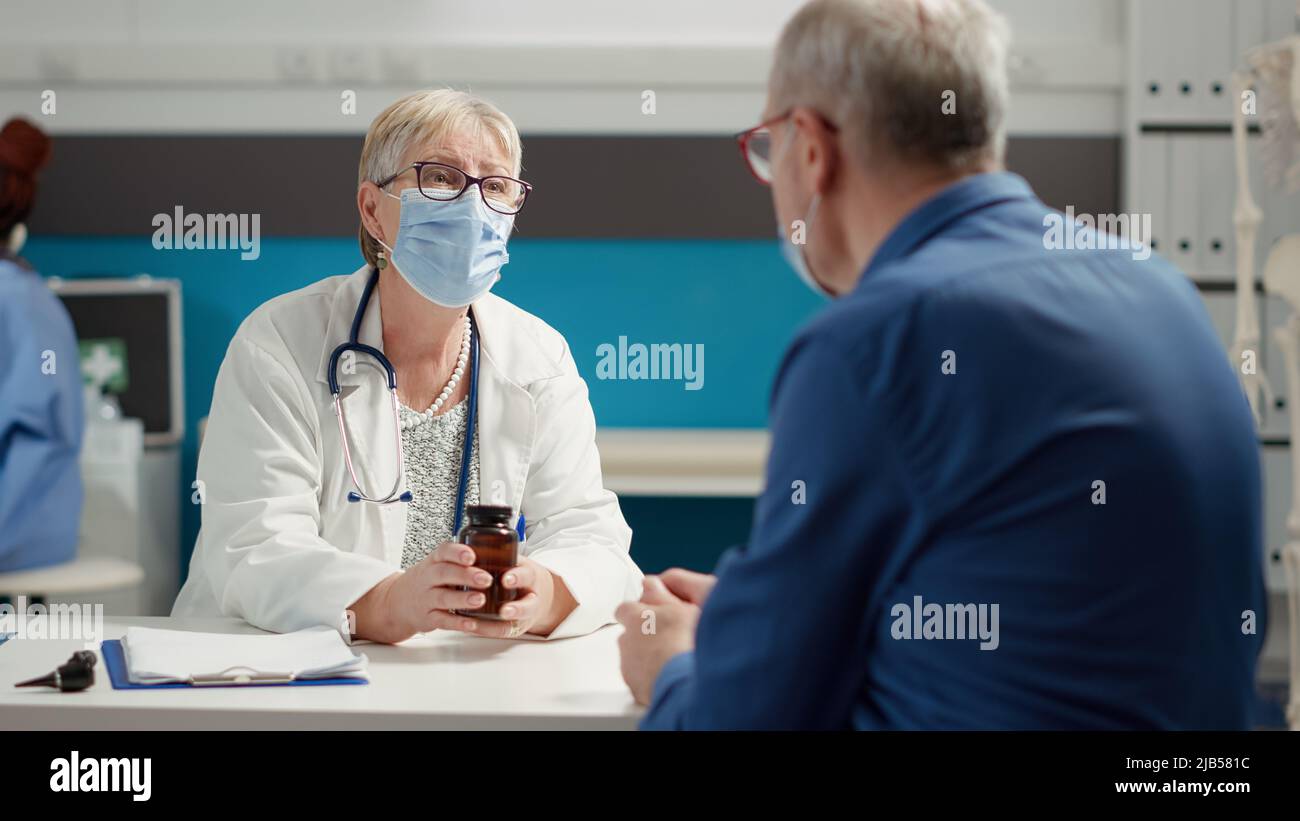 Senior doctor giving bottle of pills as prescription medicine to sick ...