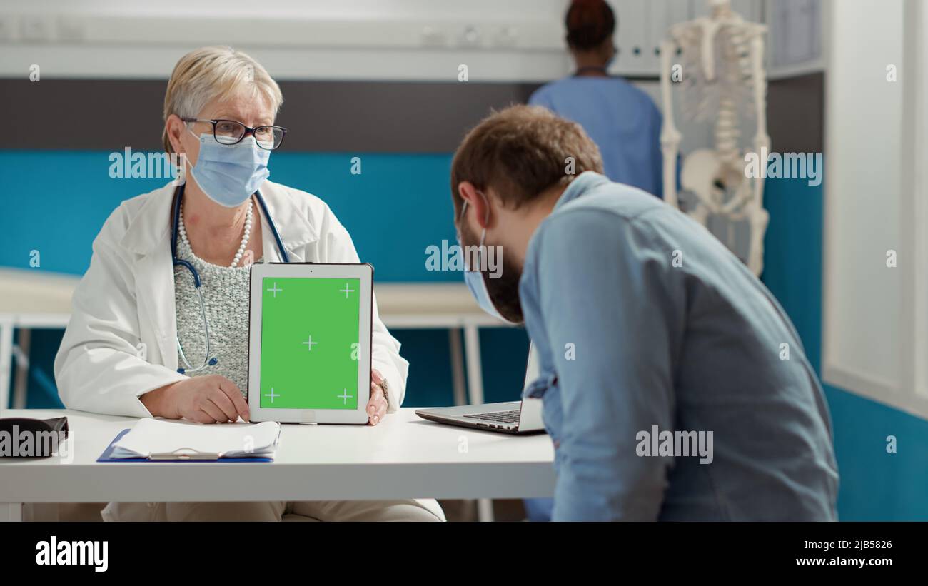 Physician and man looking at digital tablet with greenscreen in medical ...
