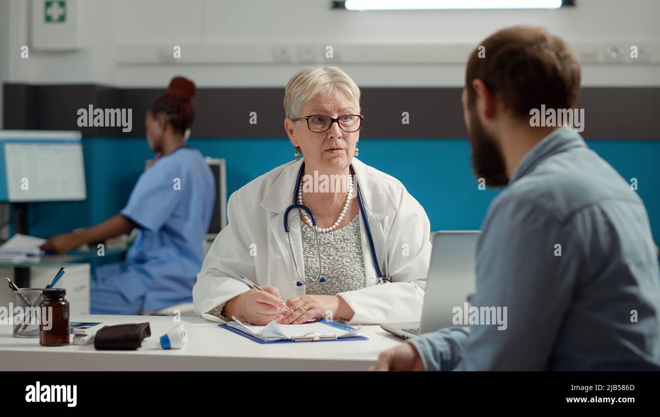 Senior doctor writing consultation information on checkup report to ...