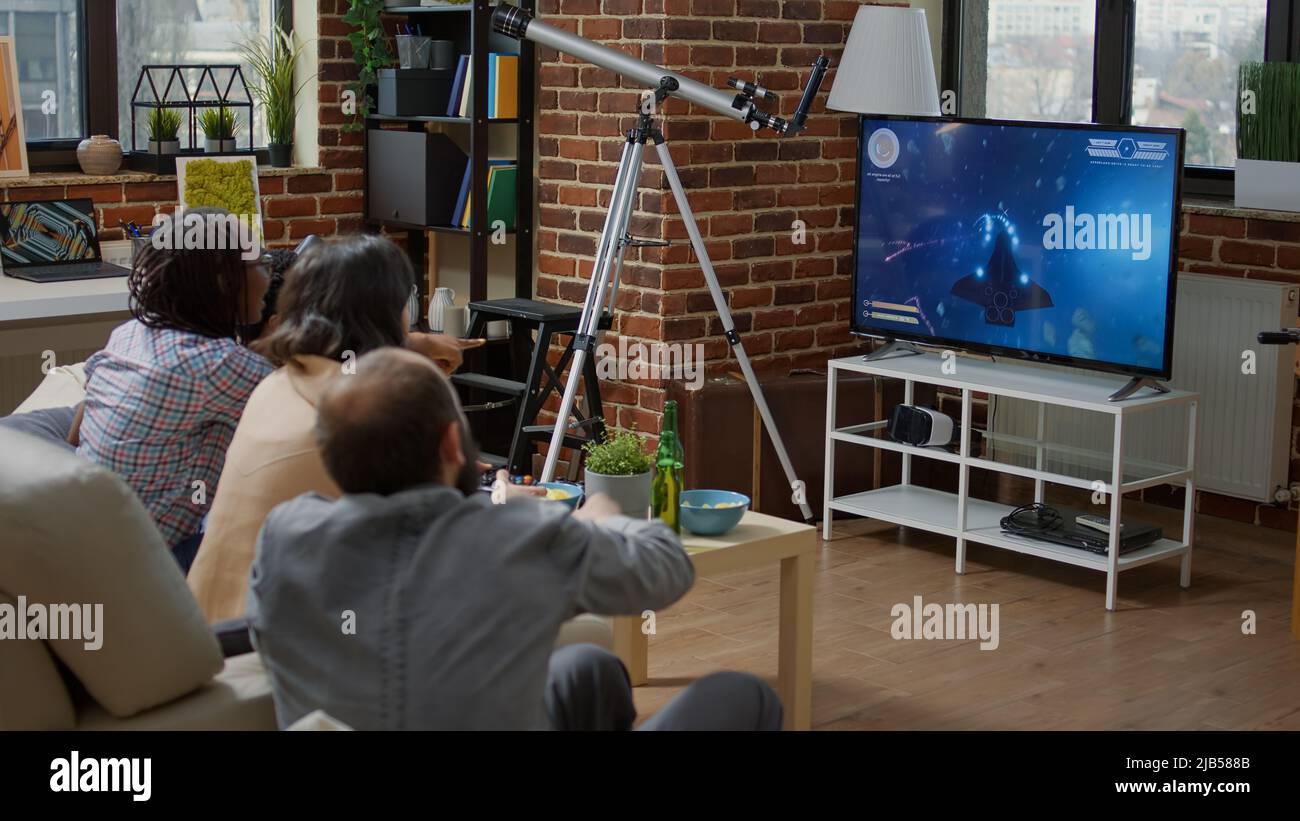 Diverse group of friends playing video games on game console, having ...