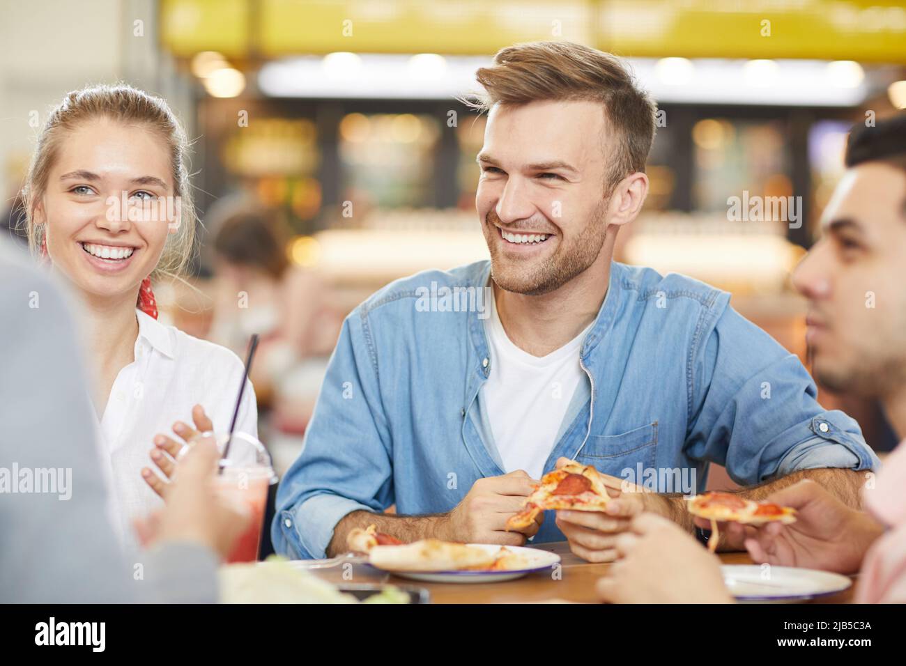 Group of cheerful excited friends sitting at table in fast food ...