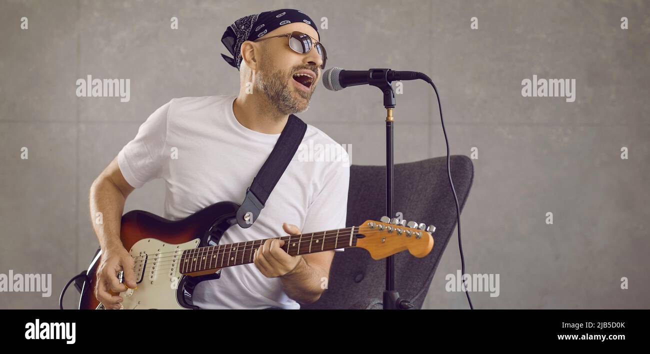 Rock musician in bandana and sunglasses playing electric guitar and ...