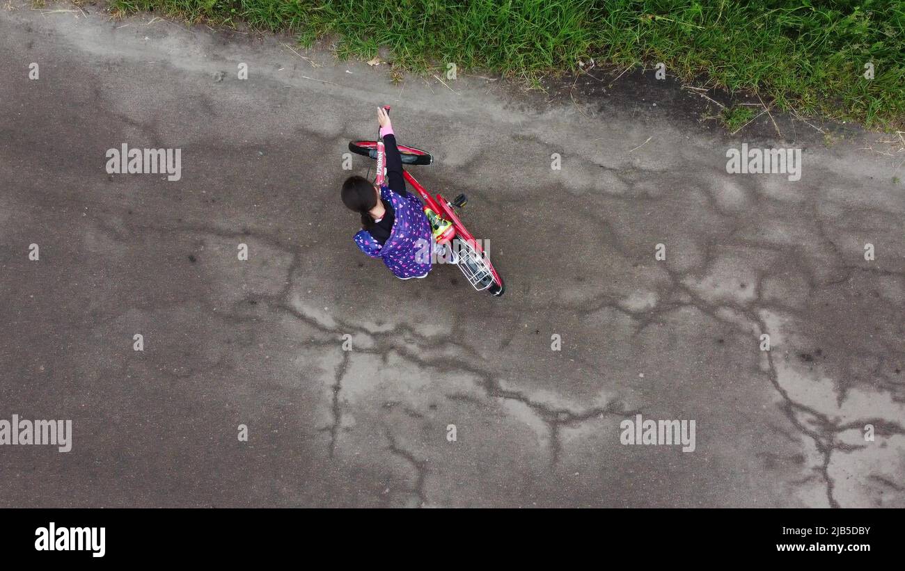 Aerial drone top view flight above girl rides bicycle on countryside ...