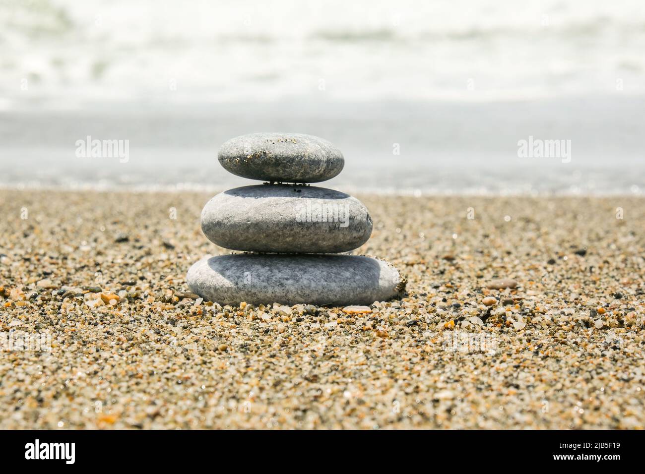 Rock balancing on ocean beach. Pyramid of pebbles on sandy shore ...