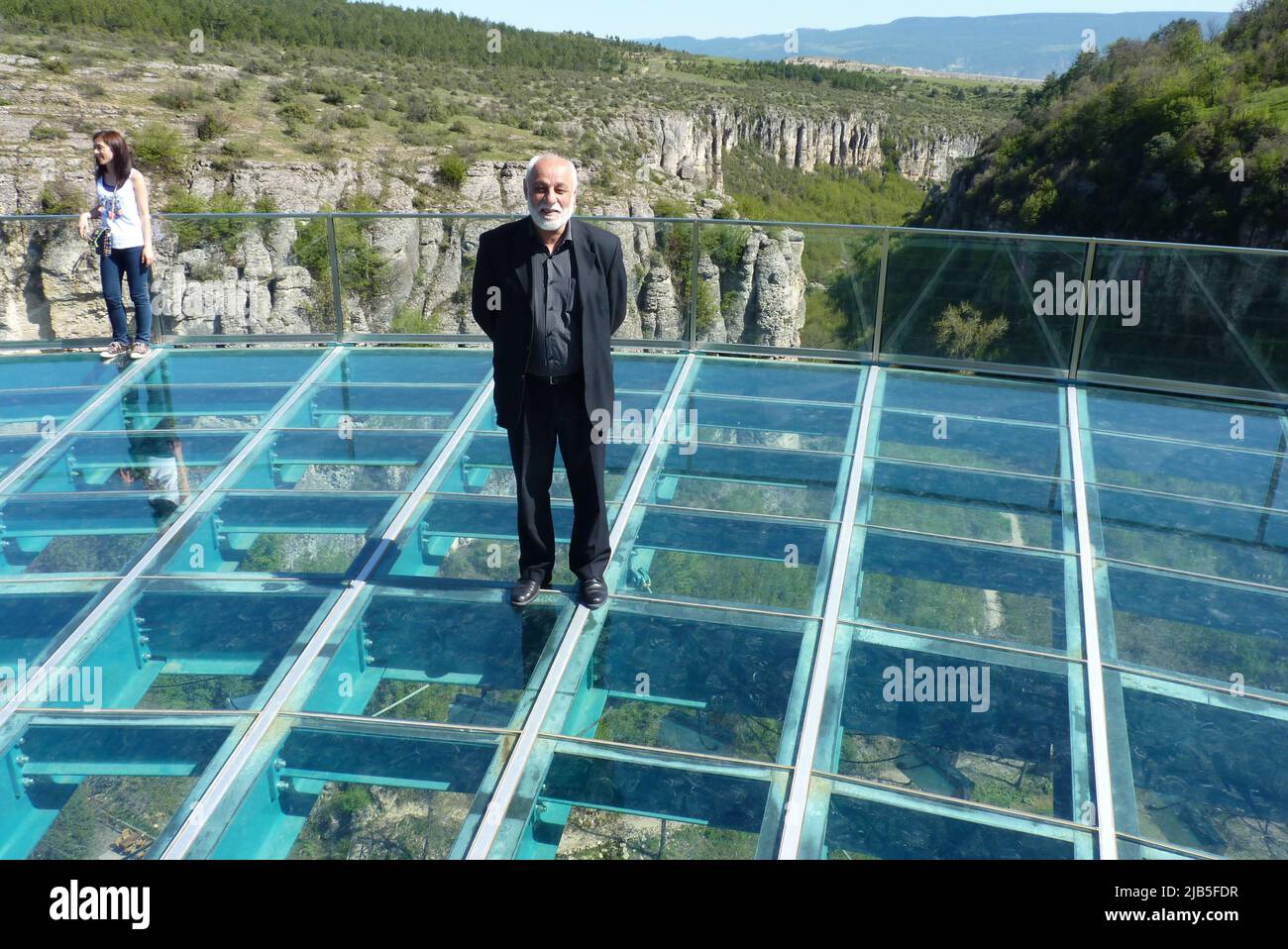 Man in Dark Suit on Glass Platform Overlooking Scenic Cliffs and ...