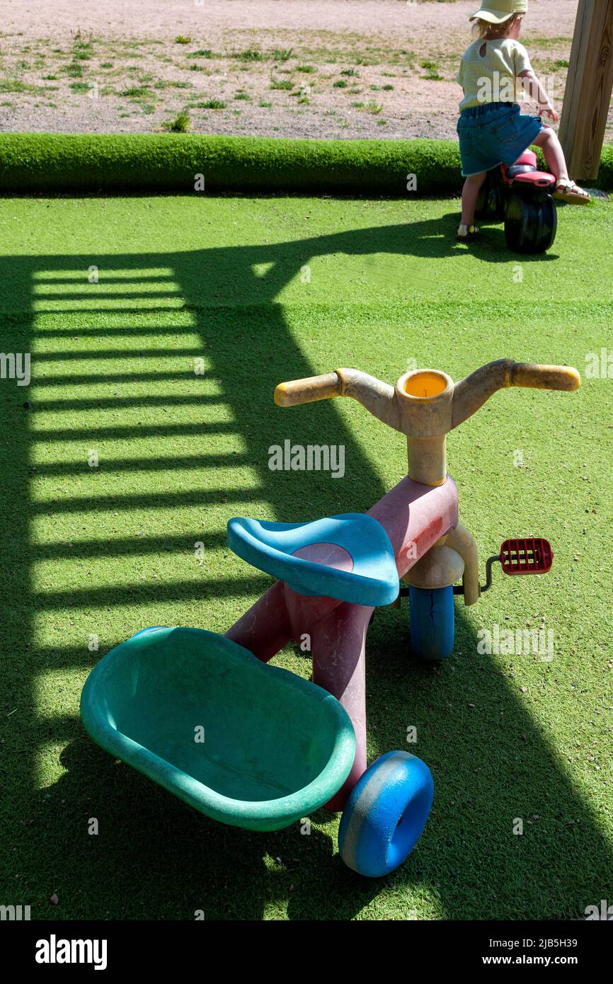 Children's colorful ride-on toys scattered on vibrant green grass in a ...