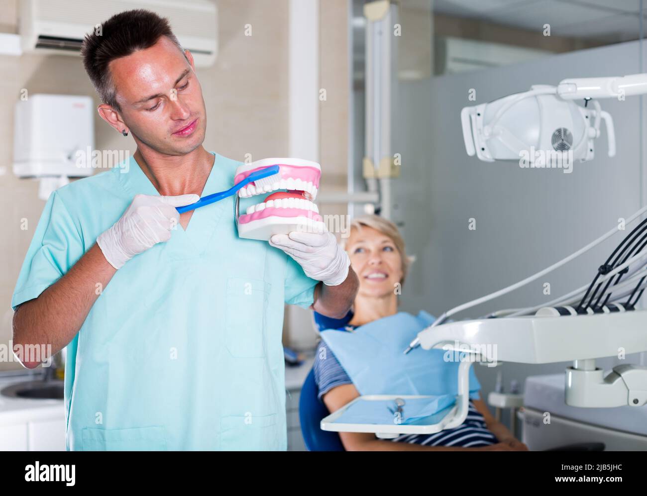 Dentist explaining tooth brushing on dental model Stock Photo - Alamy