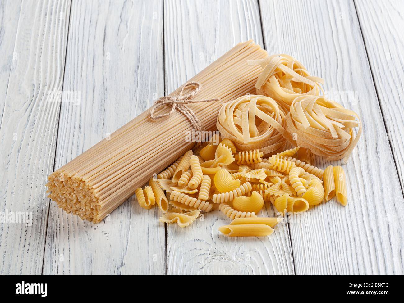 Different types and shapes of Italian pasta on white wooden background ...