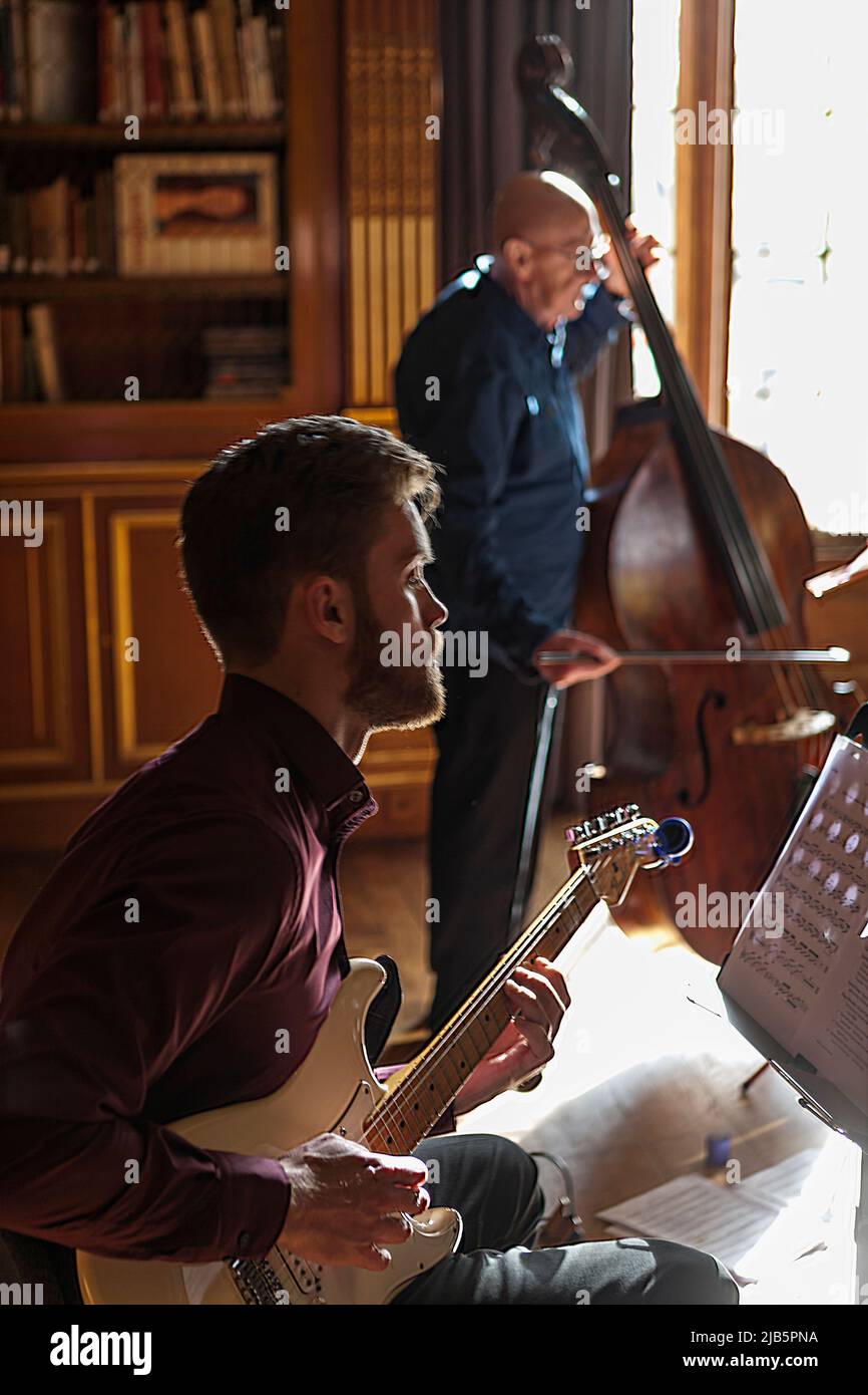 Two musicians (guitarist and double bass player) rehearsing a piece for ...