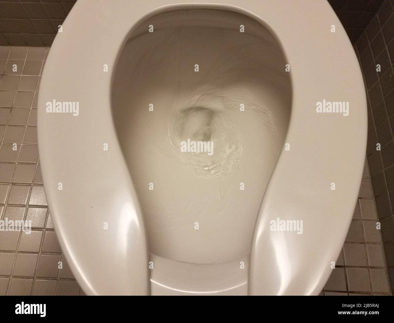 white toilet with water being flushed in bathroom Stock Photo - Alamy