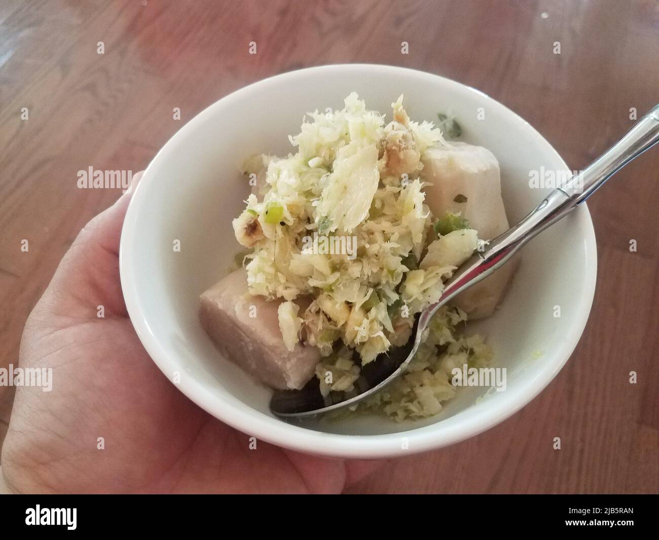 bowl with codfish and root vegetables and spoon over wood floor puerto ...