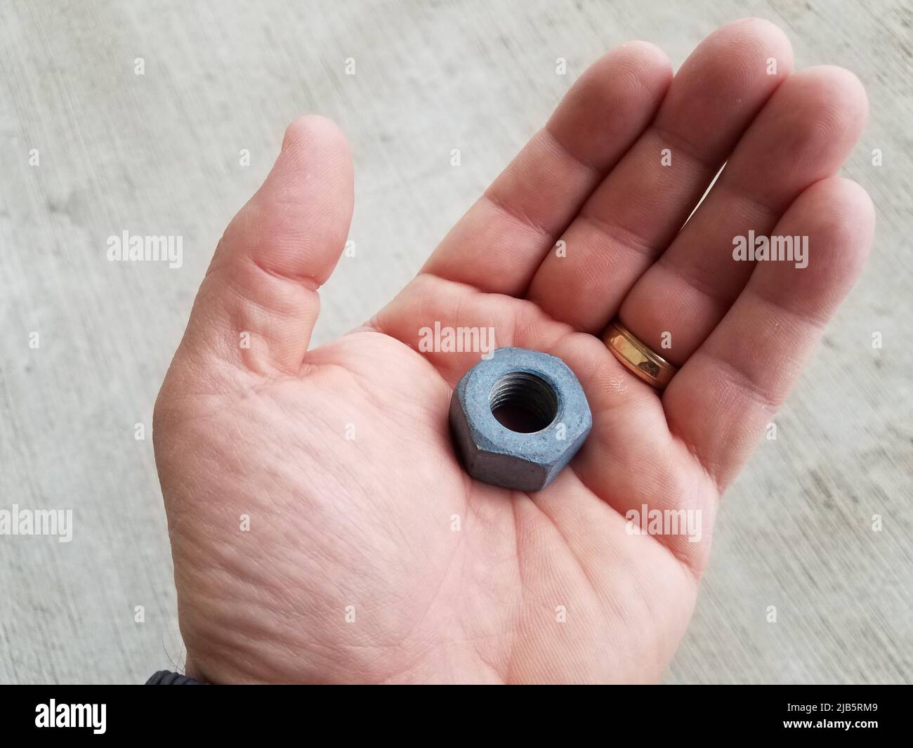palm of hand holding metal bolt over grey cement Stock Photo - Alamy