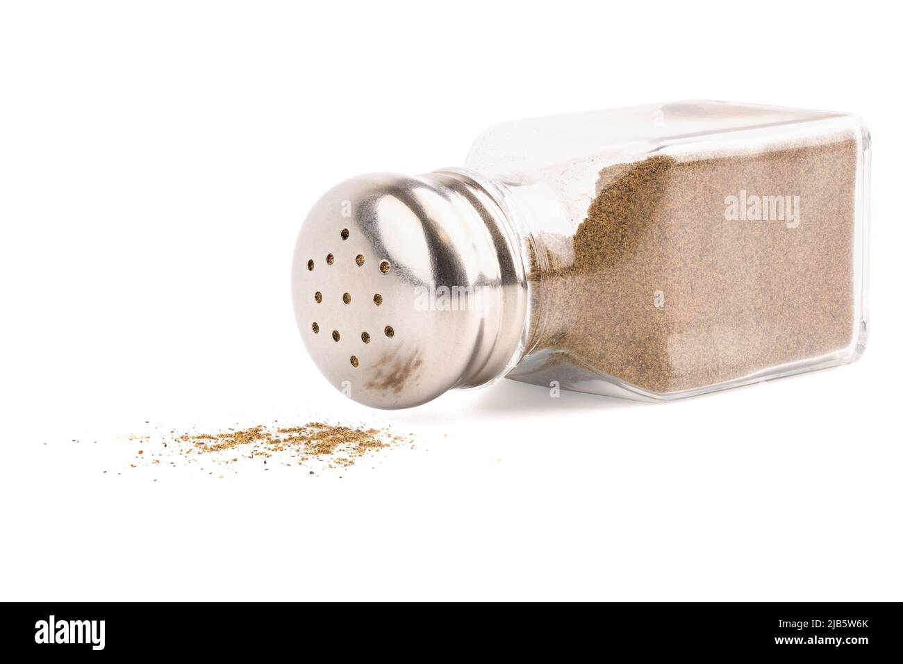 glass pepper pot with ground black pepper dropped on its side isolated ...