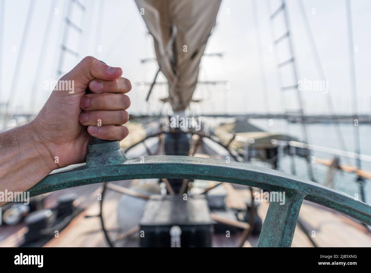 Left hand squeezing ship wheel with blurred background Stock Photo - Alamy