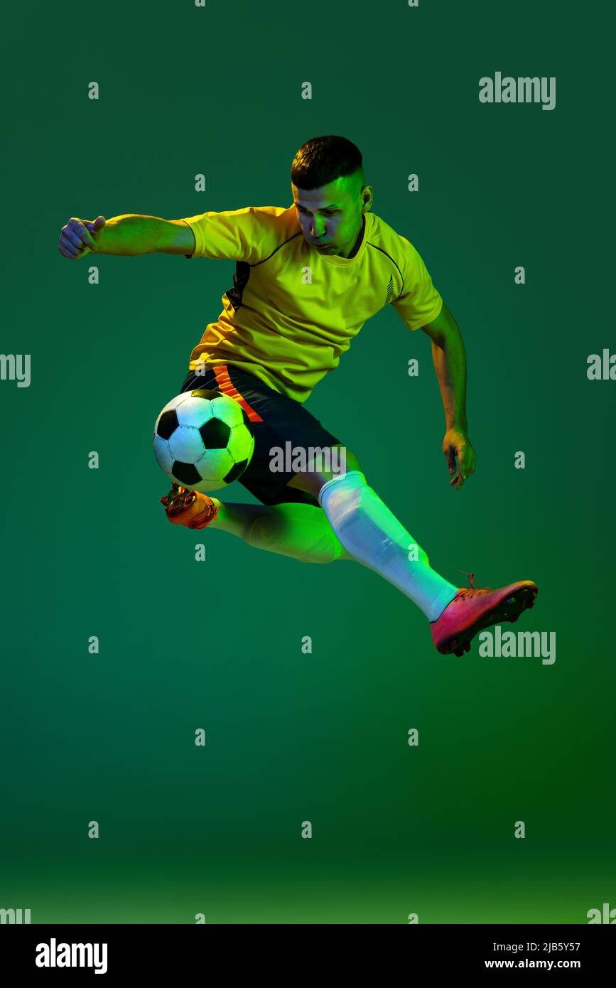 Studio shot of young professional male football soccer player in motion ...