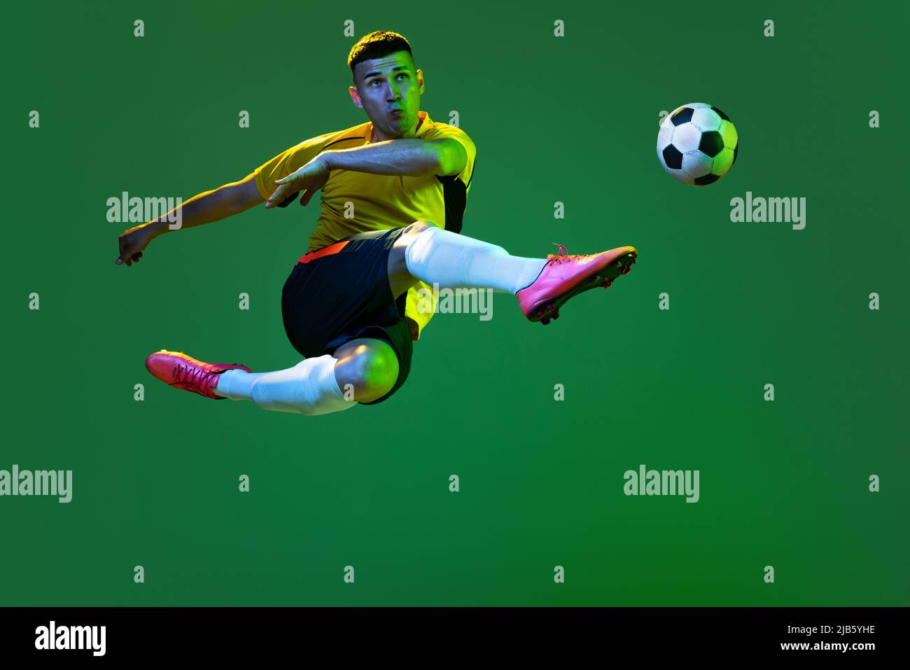Studio shot of young professional male football soccer player in motion ...