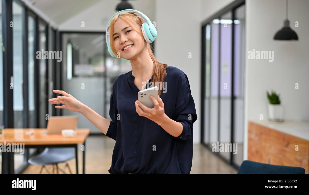 Cheerful and beautiful Asian millennial woman enjoying with the music ...