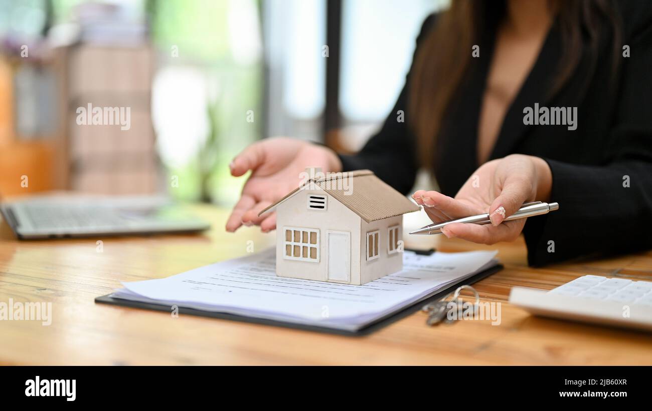 A beautiful house model on a worktable with documents and female real ...