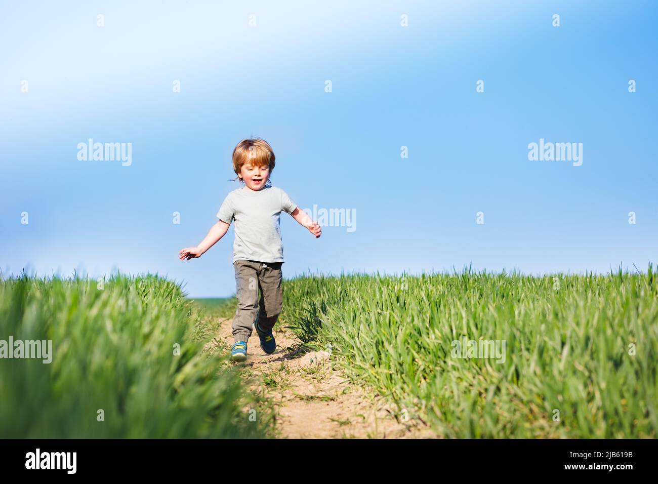 Little boy run smiling in the clear spring field Stock Photo - Alamy