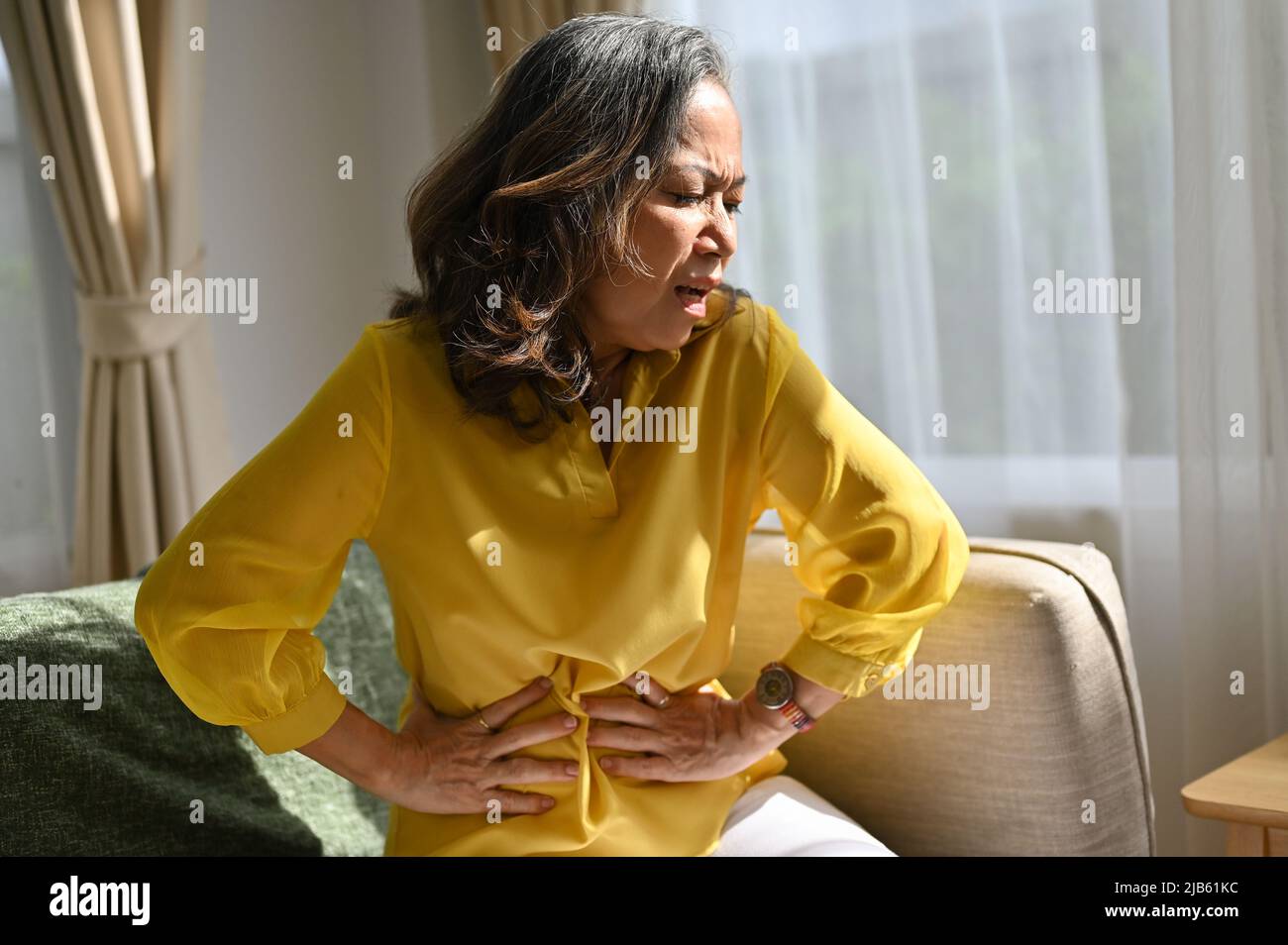 Unhappy asian aged woman feeling discomfort in abdomen, stomach ache ...