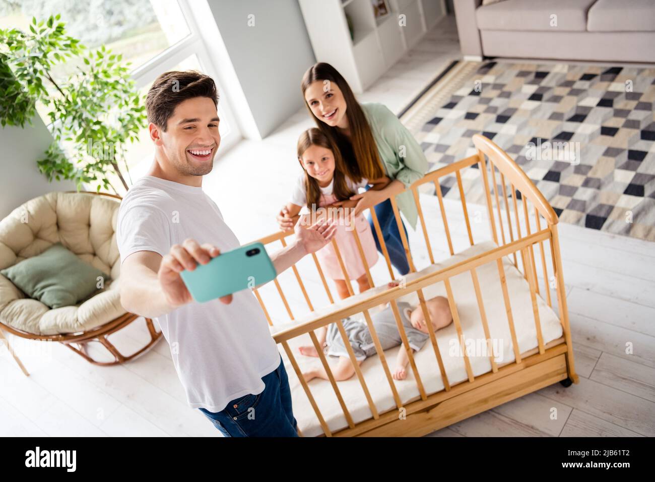 Photo of full beautiful family make selfie stand near sleeping toddler ...