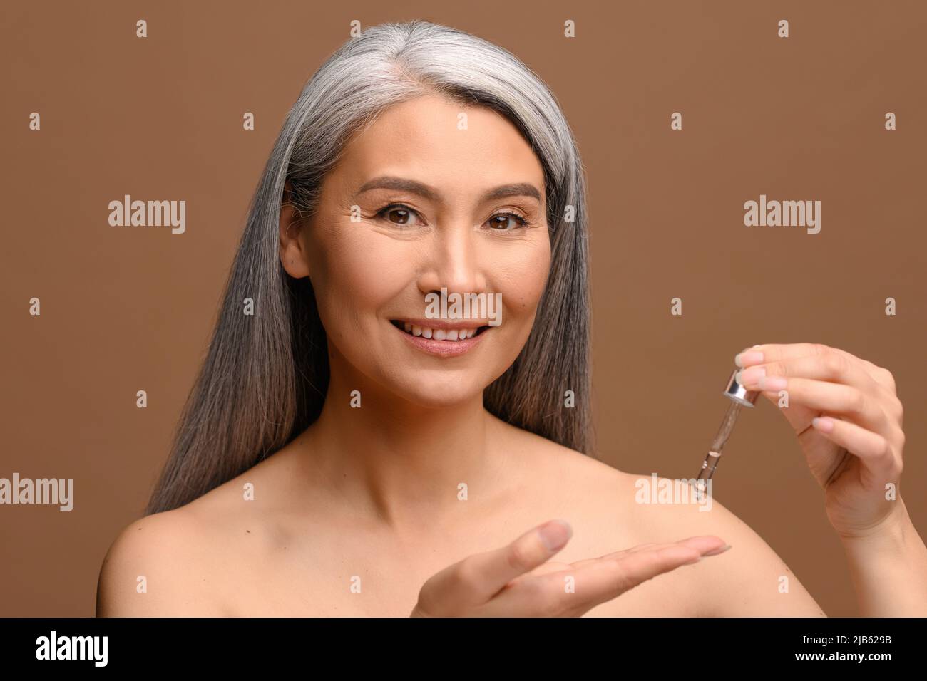 Charming Asian 40s lady using anti-aging complex with hyaluronic acid ...