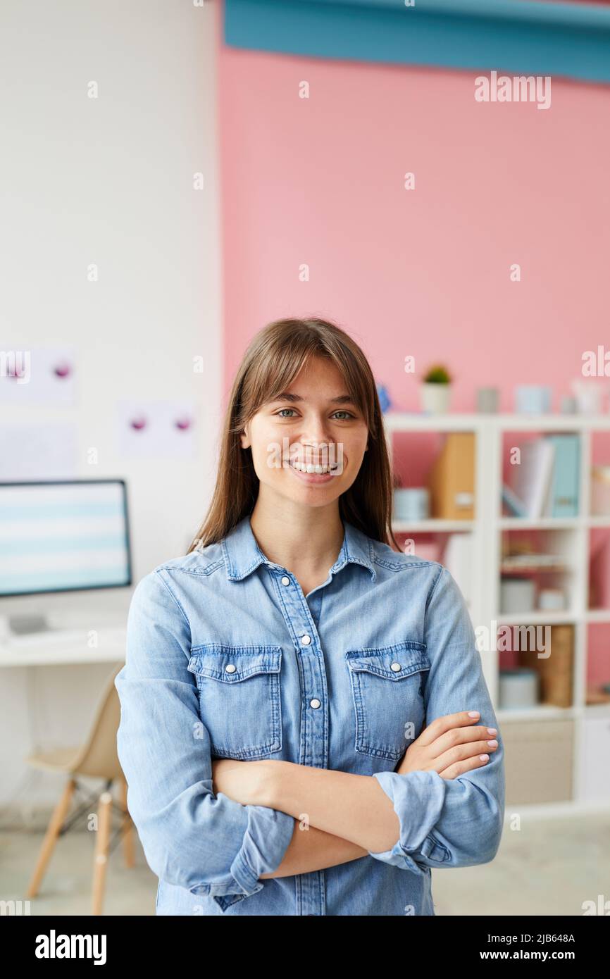 Positive pretty young lady crossing arms on chest and standing in cute ...