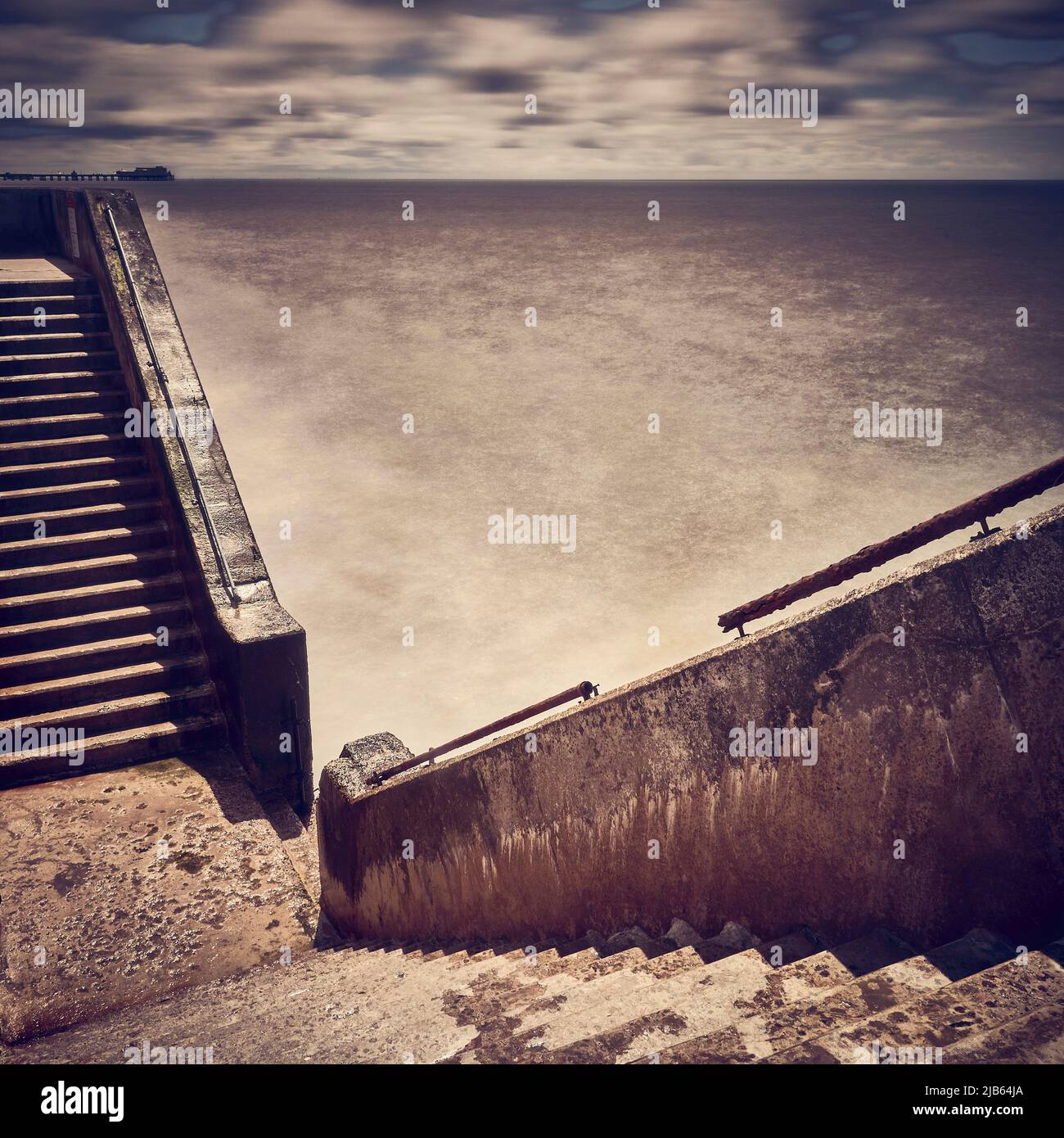 Old rotting concrete steps and railings down to beach at high tide in ...