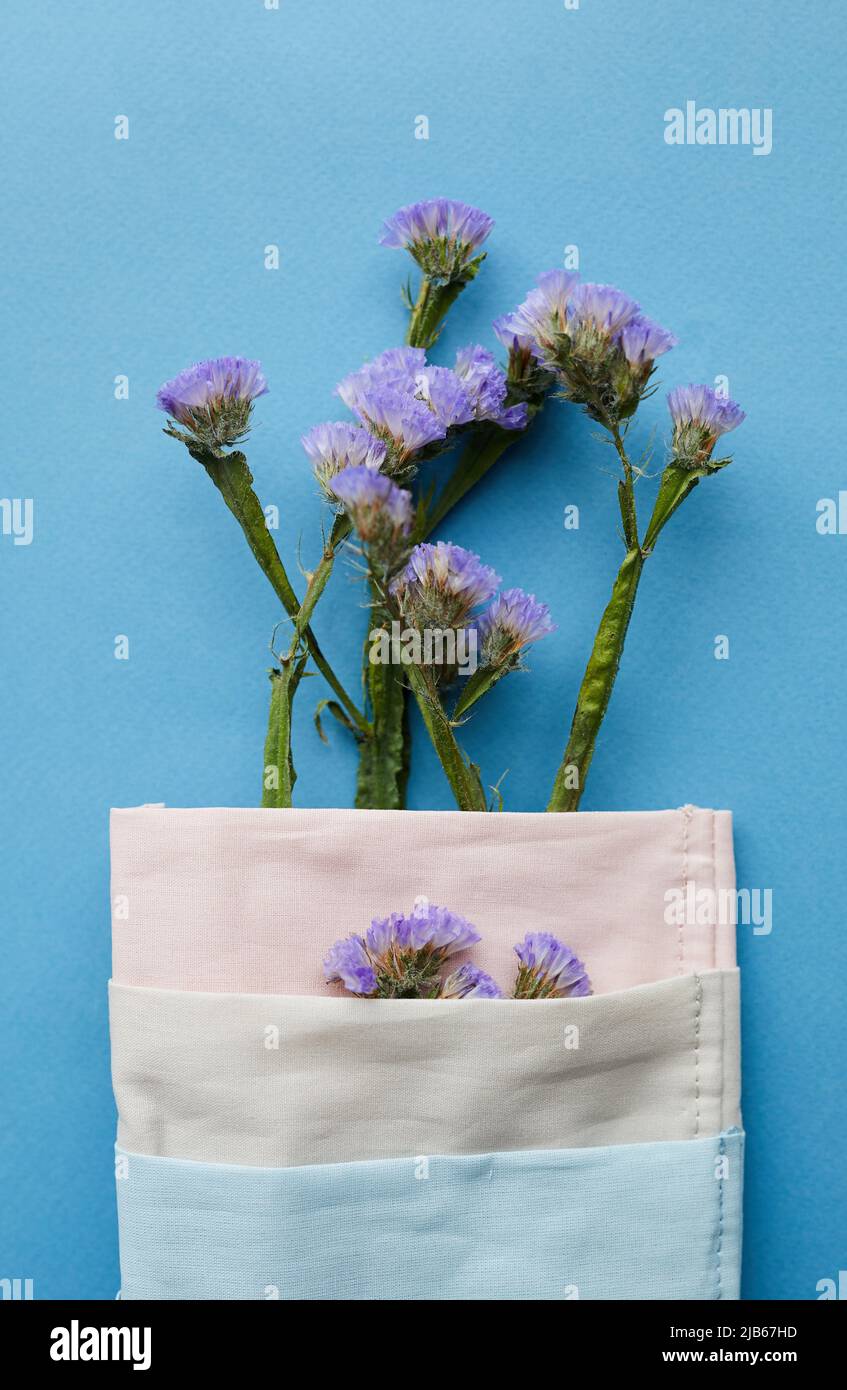 Close-up of cute blue flowers wrapped in napkin placed on served table ...