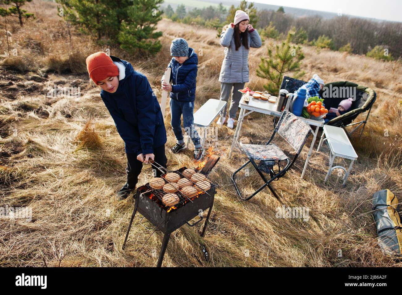 Family barbecuing on a deck in the pine forest. Bbq day with grill ...