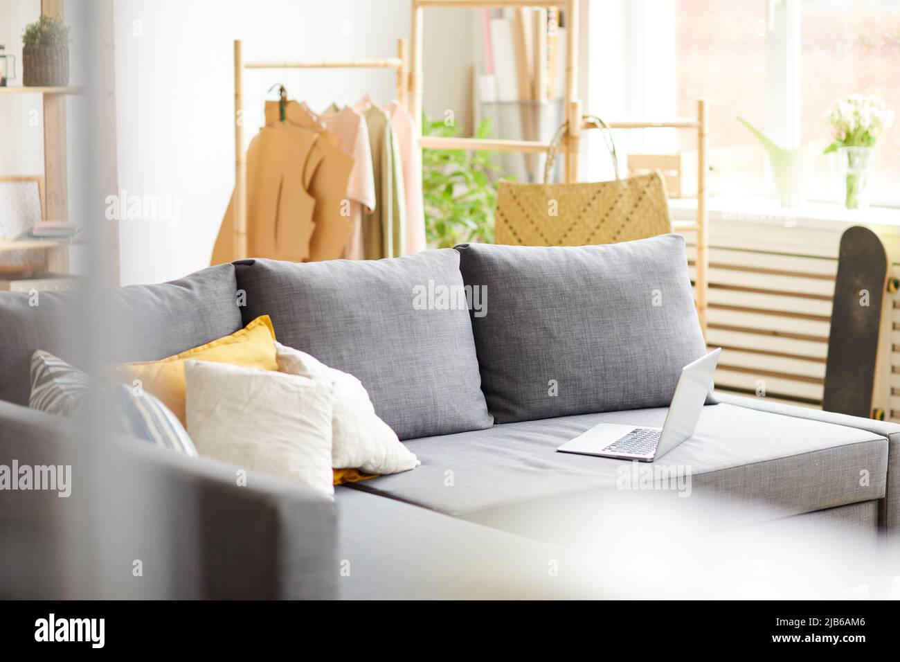 Interior of cozy clothing store with comfortable sofa, clothes racks ...