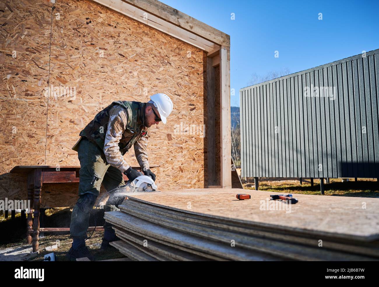 Carpenter using circular saw for cutting wooden OSB board. Man worker ...