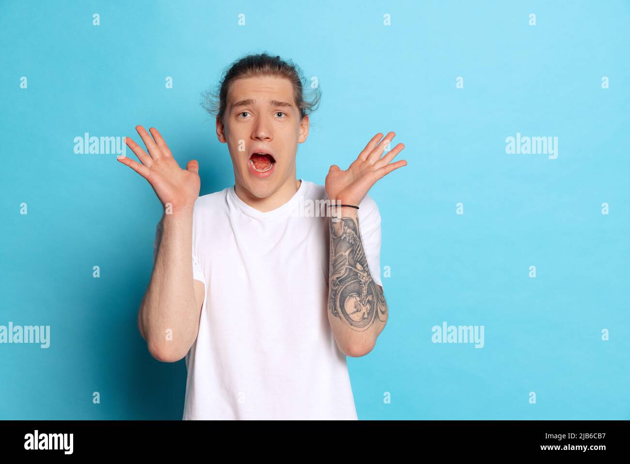 Shocked, surprised young emotional man with long curly hair shouting ...