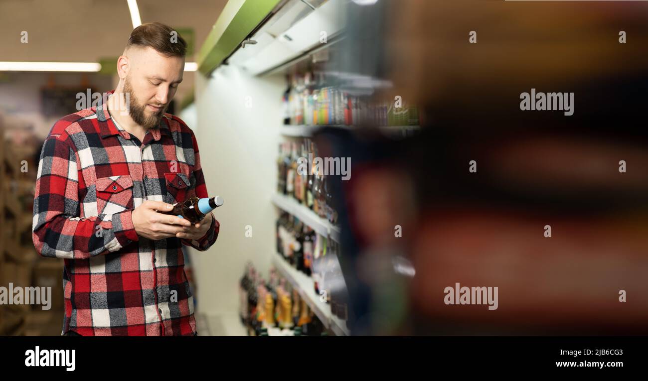 handsome bearded man chooses beer in the supermarket. Customer buying ...
