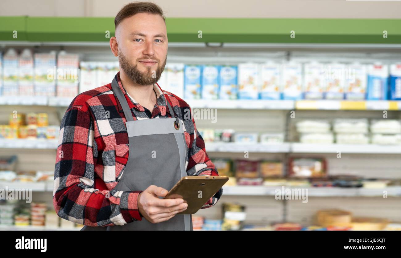 Portrait of sales clerk wearing apron using a digital tablet with store ...