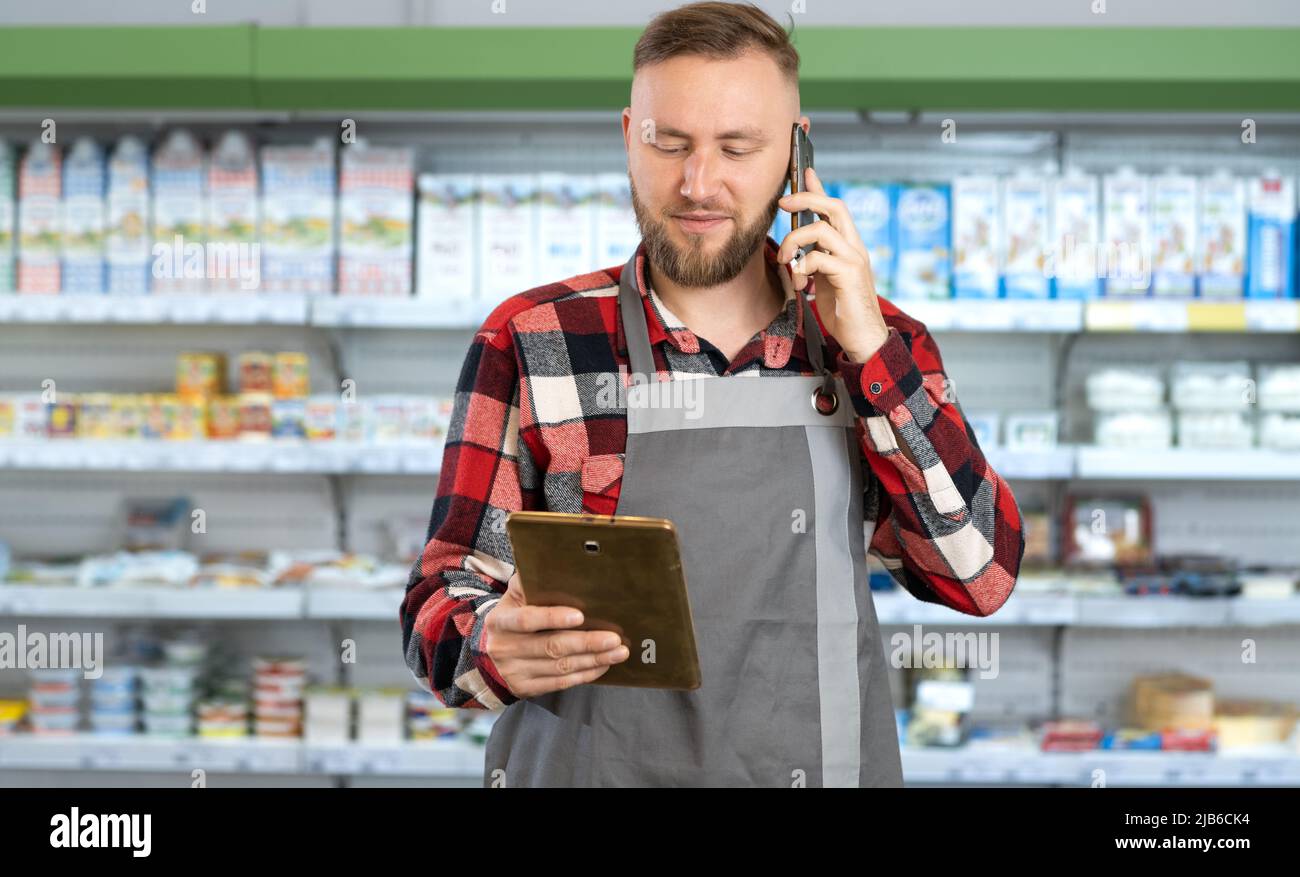 Professional supermarket clerk using a touch screen tablet and working ...