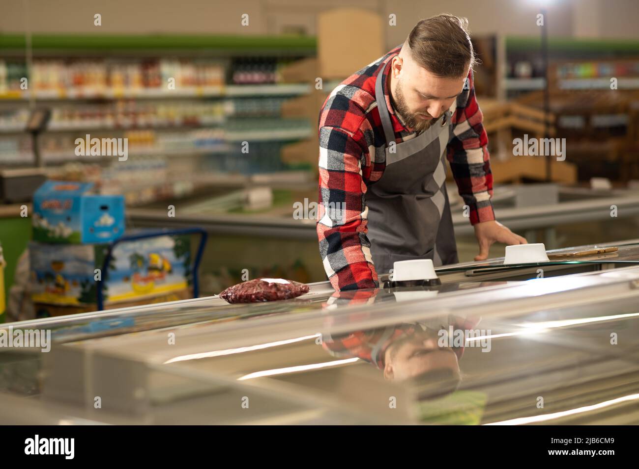 sale, consumerism and people concept - frozen food department worker in ...