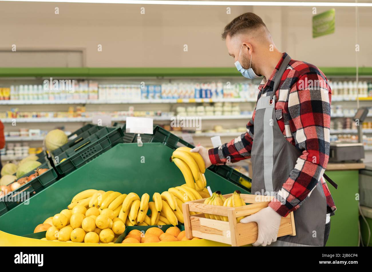 Caucasian employee in fruits store with citrus and bananas, supermarket ...