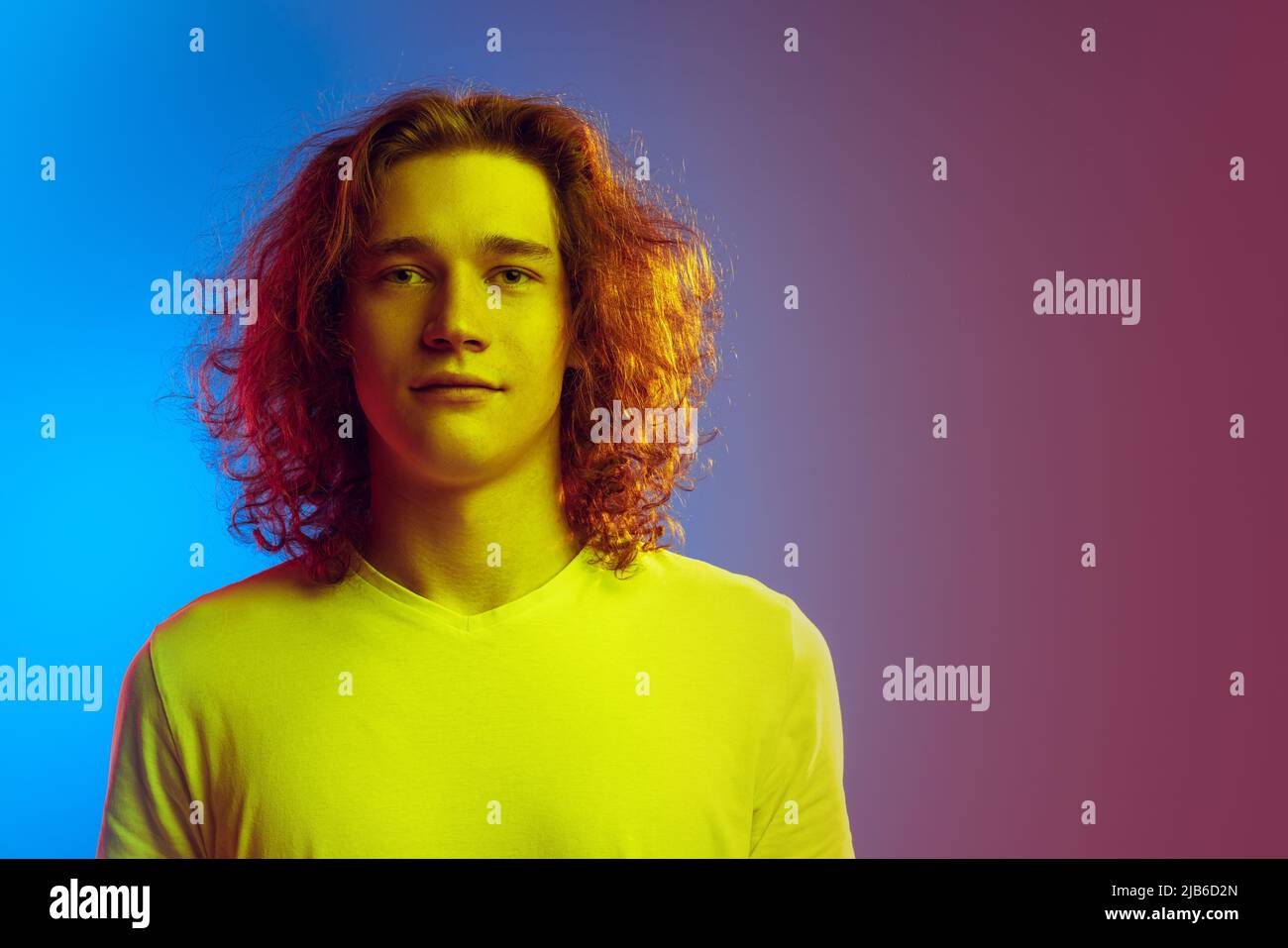 Young attractive man with long curly hair posing isolated on gradient ...
