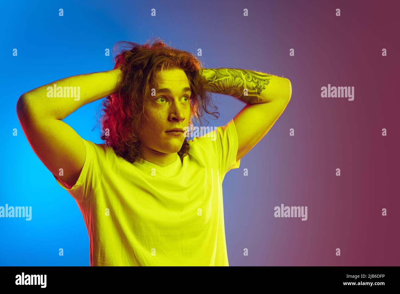 Young attractive man with long curly hair posing isolated on gradient ...