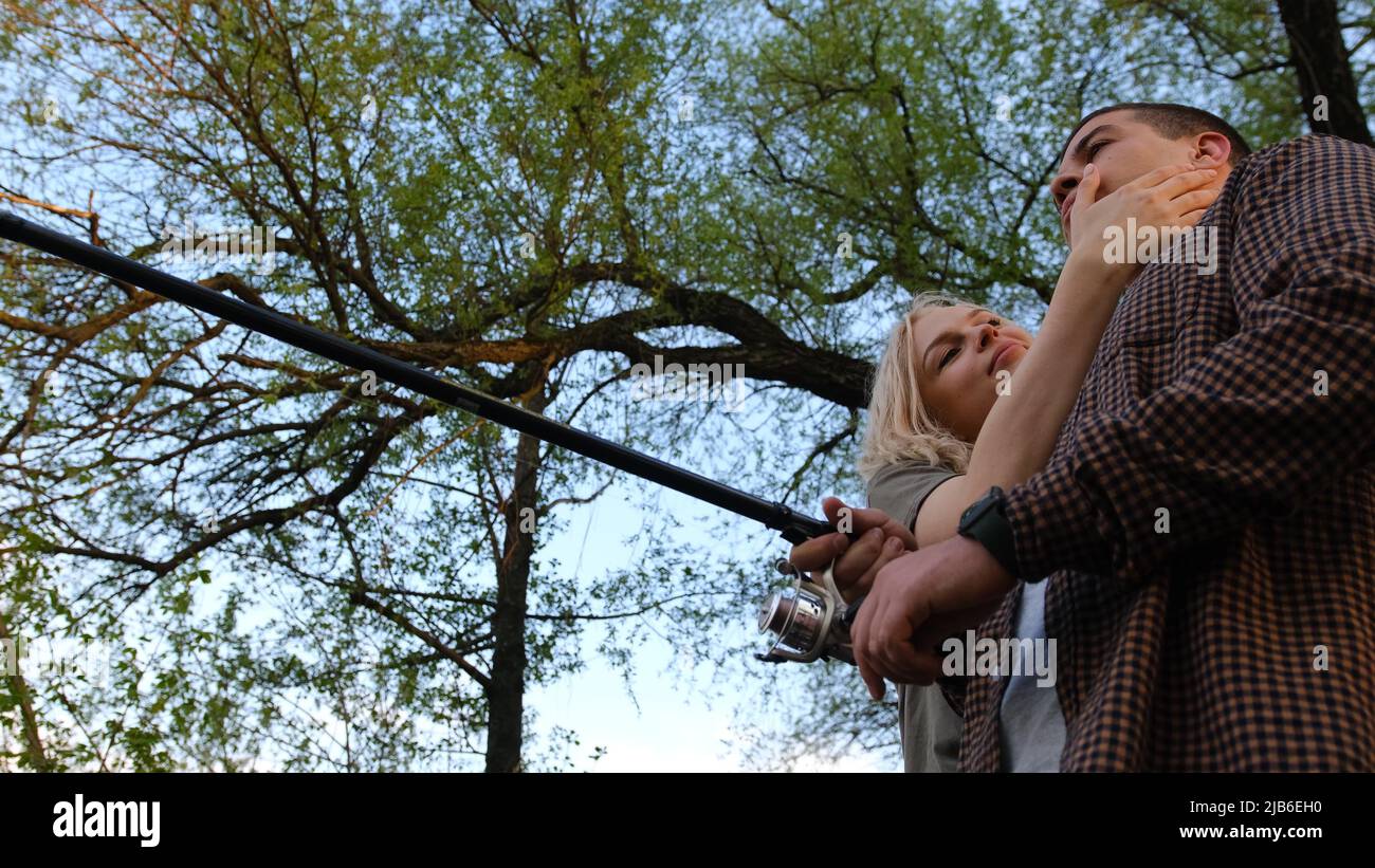 lovely young couple fishing together by a lake, river fooling and smil ...
