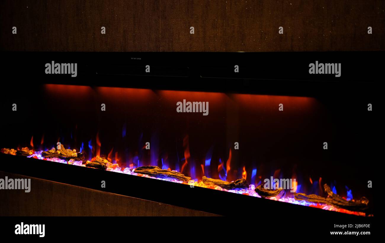 Side view on electric fireplace with artificial sparkling flame, decor ...