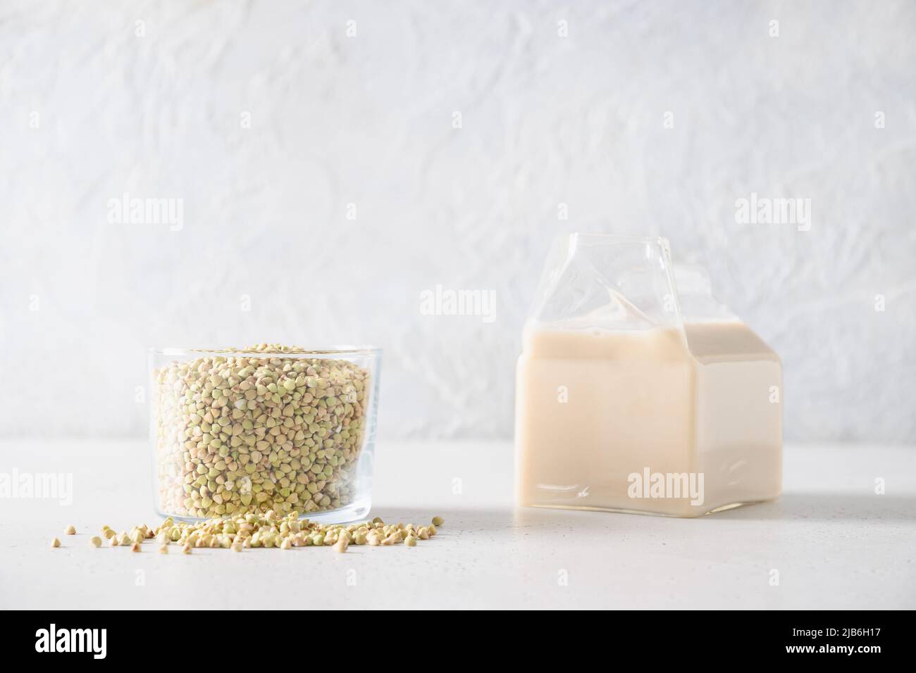 Vegan milk from raw buckwheat groats in glass on gray background. Close ...