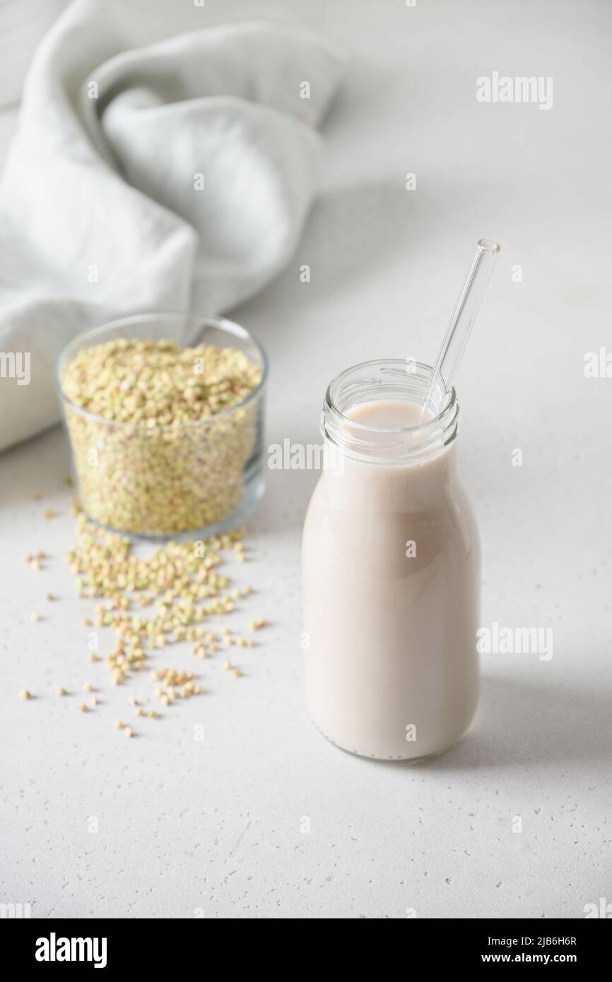 Vegan milk in glass bottle of green raw buckwheat groats on white ...
