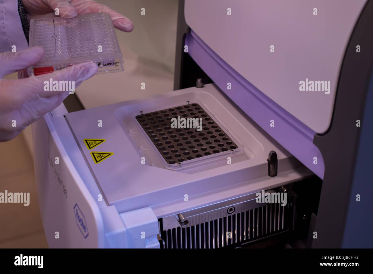 Researcher holding a plate of cells and putting it on a machine Stock ...