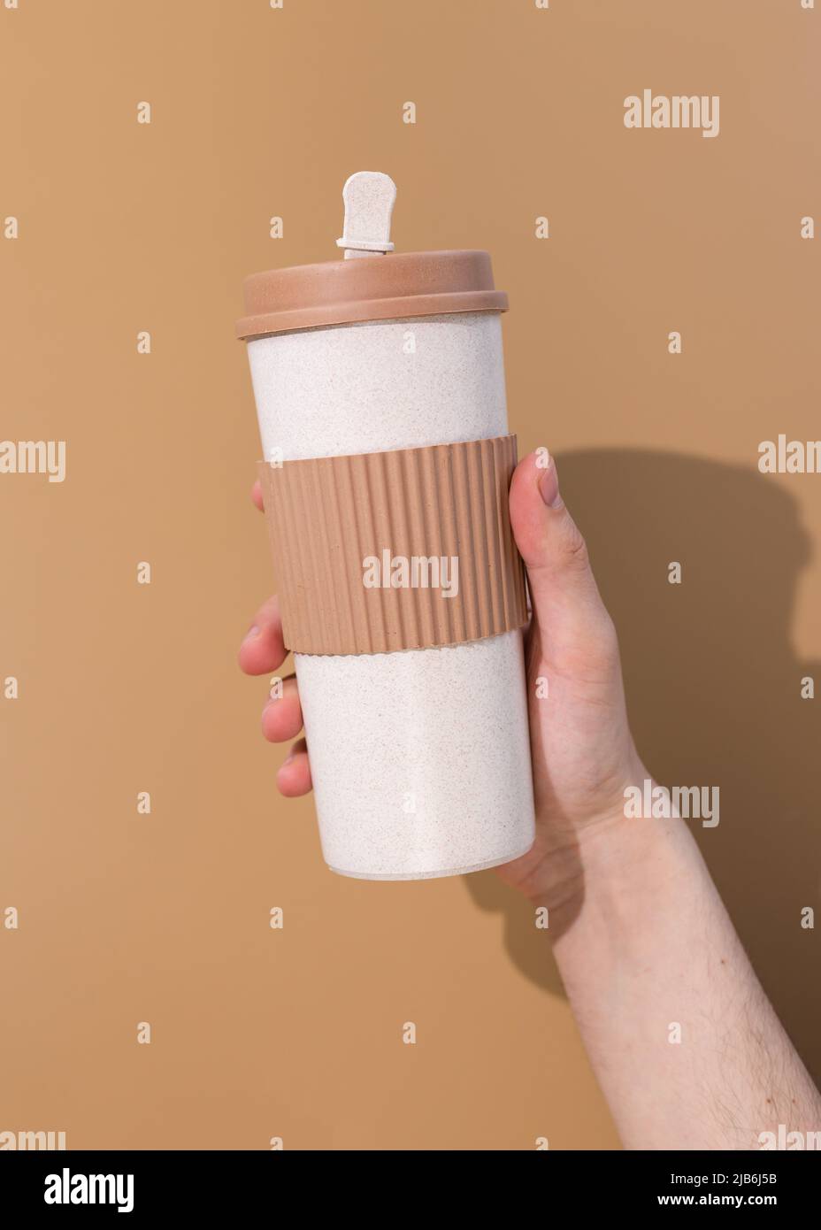 Refillable cup in young mans hand on beige background. Concept of ...
