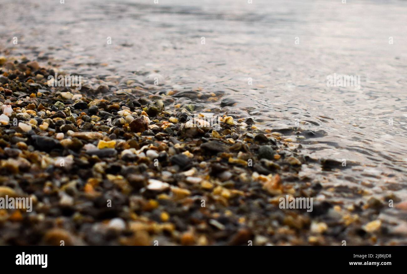 Close up photo of waves on colorful rocks in the beach Stock Photo - Alamy