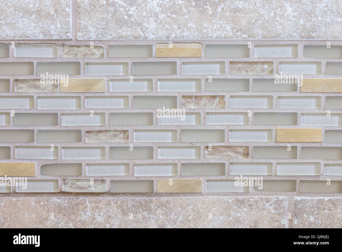 Clear colored glass and metallic small accent strip tiles in a master ...