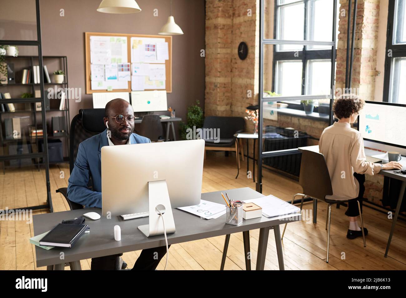 Business people sitting at their workplaces and working on computers at ...