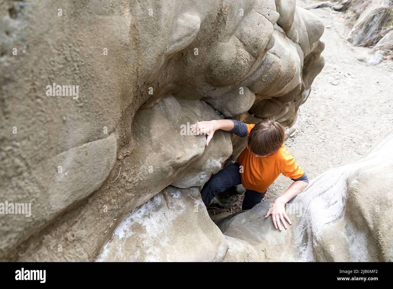 Boy climbing through the narrow gap in Bear gorge, Datvis Khevi ...